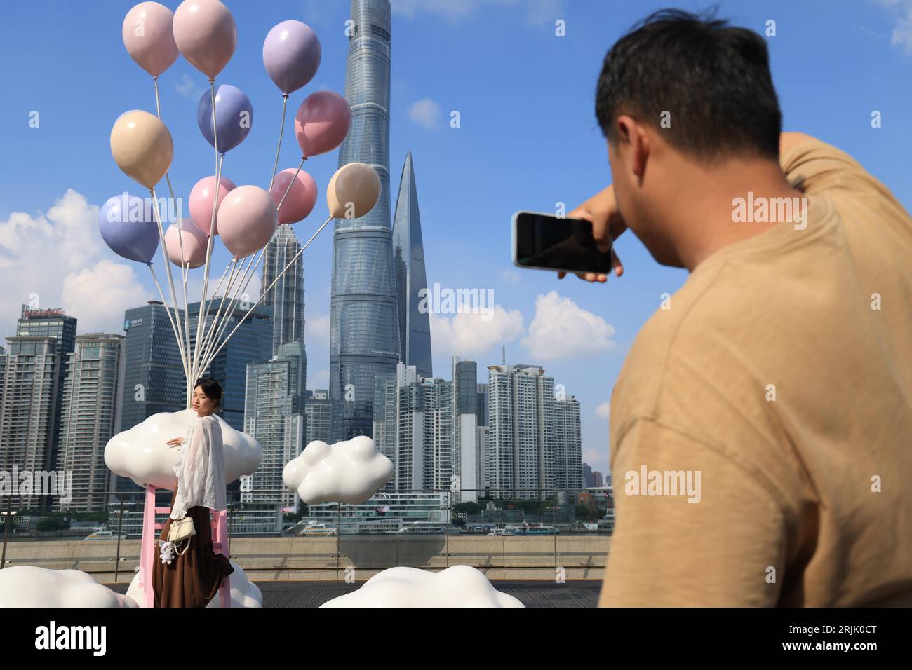 Tourists take photos of a large balloon art installation at the Bund in ...