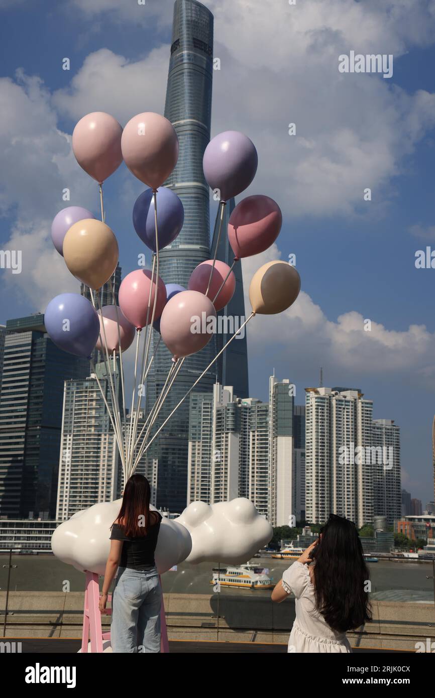 Tourists take photos of a large balloon art installation at the Bund in ...