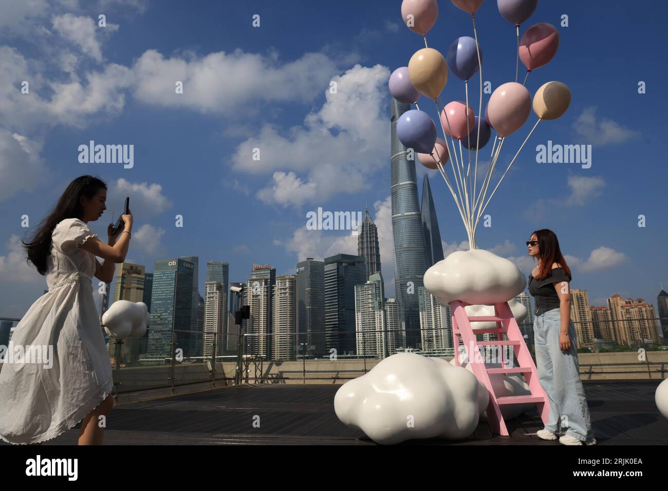 Tourists take photos of a large balloon art installation at the Bund in ...