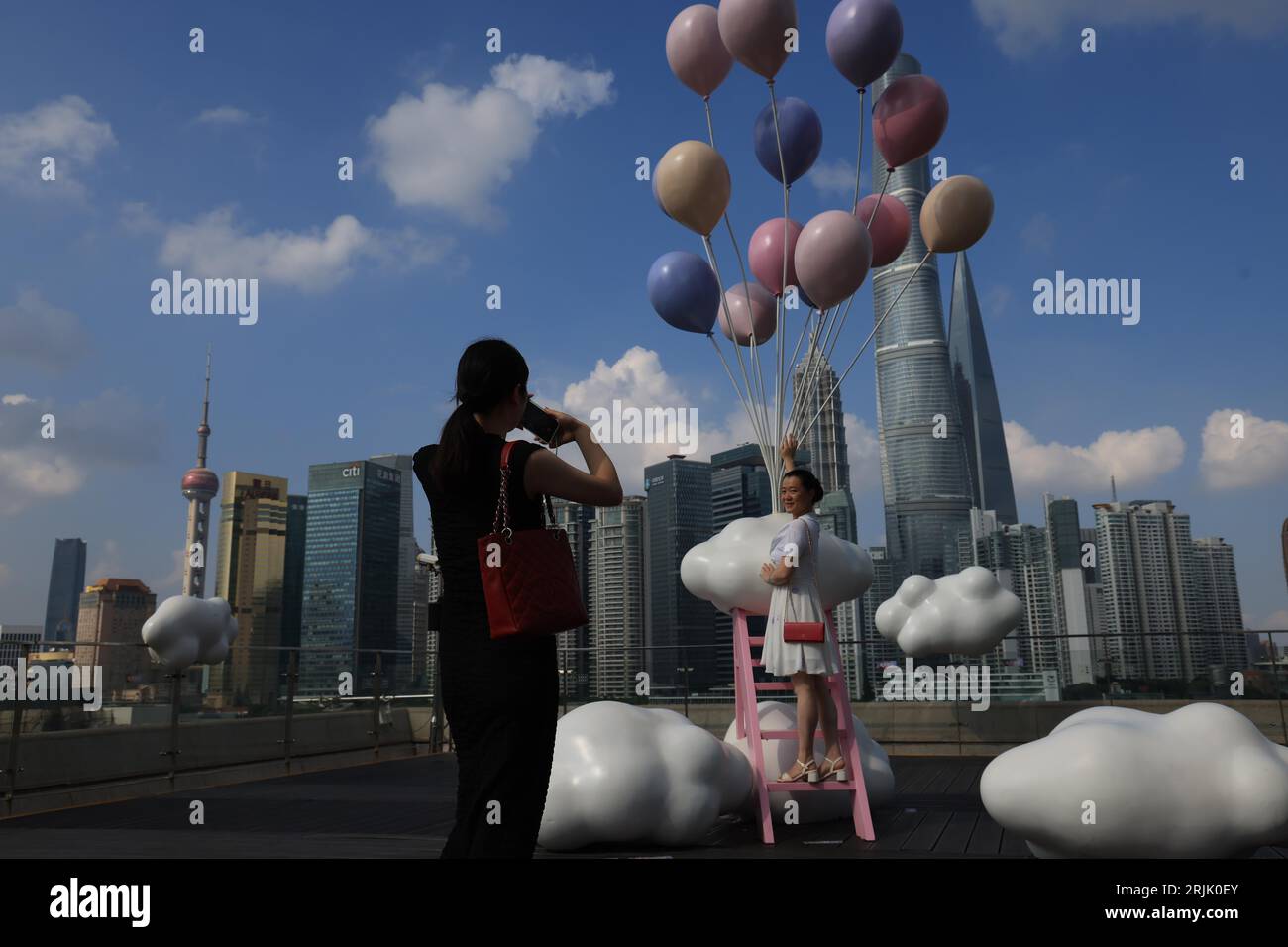 Tourists take photos of a large balloon art installation at the Bund in ...