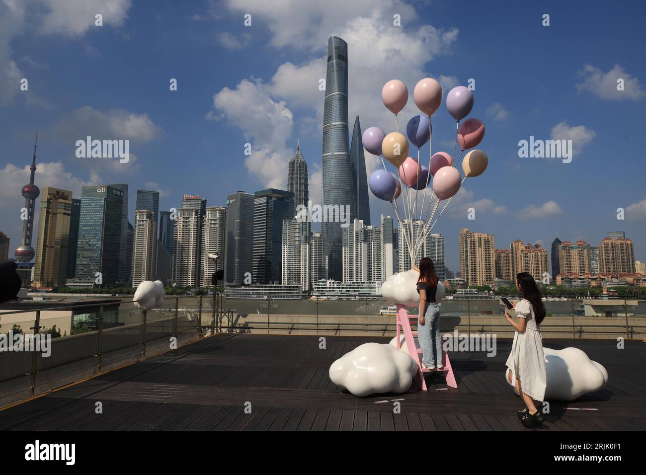 Tourists take photos of a large balloon art installation at the Bund in ...