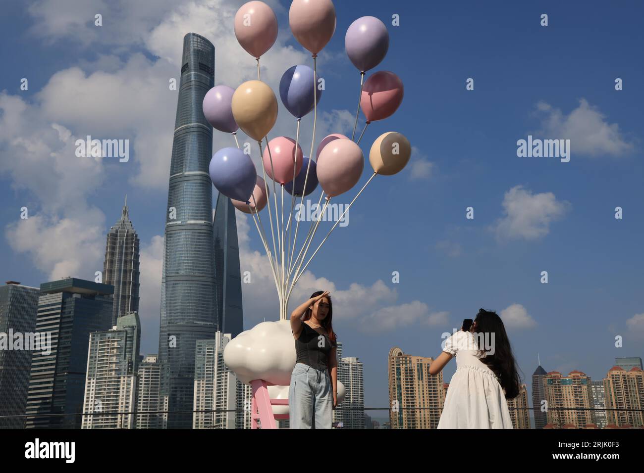 Tourists take photos of a large balloon art installation at the Bund in ...