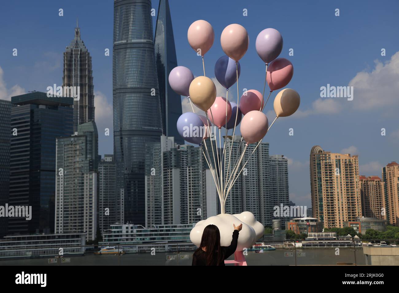 Tourists take photos of a large balloon art installation at the Bund in ...