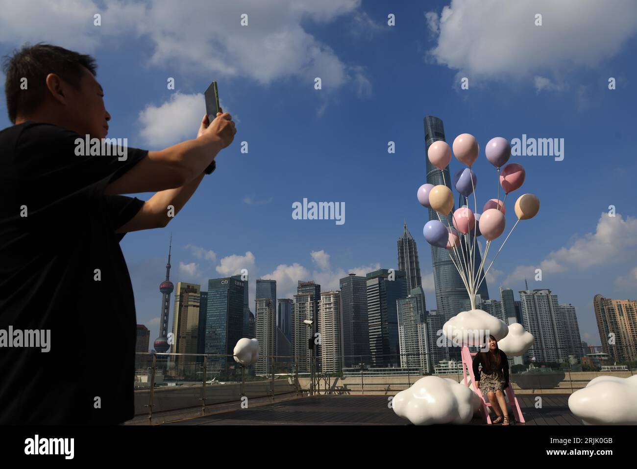 Tourists take photos of a large balloon art installation at the Bund in ...