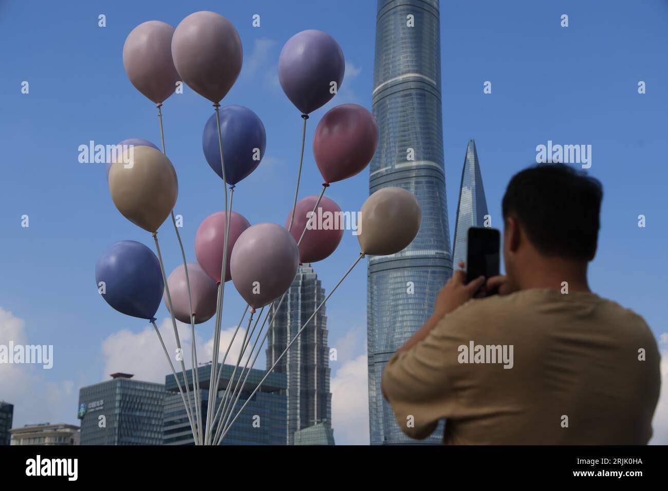 Tourists take photos of a large balloon art installation at the Bund in ...