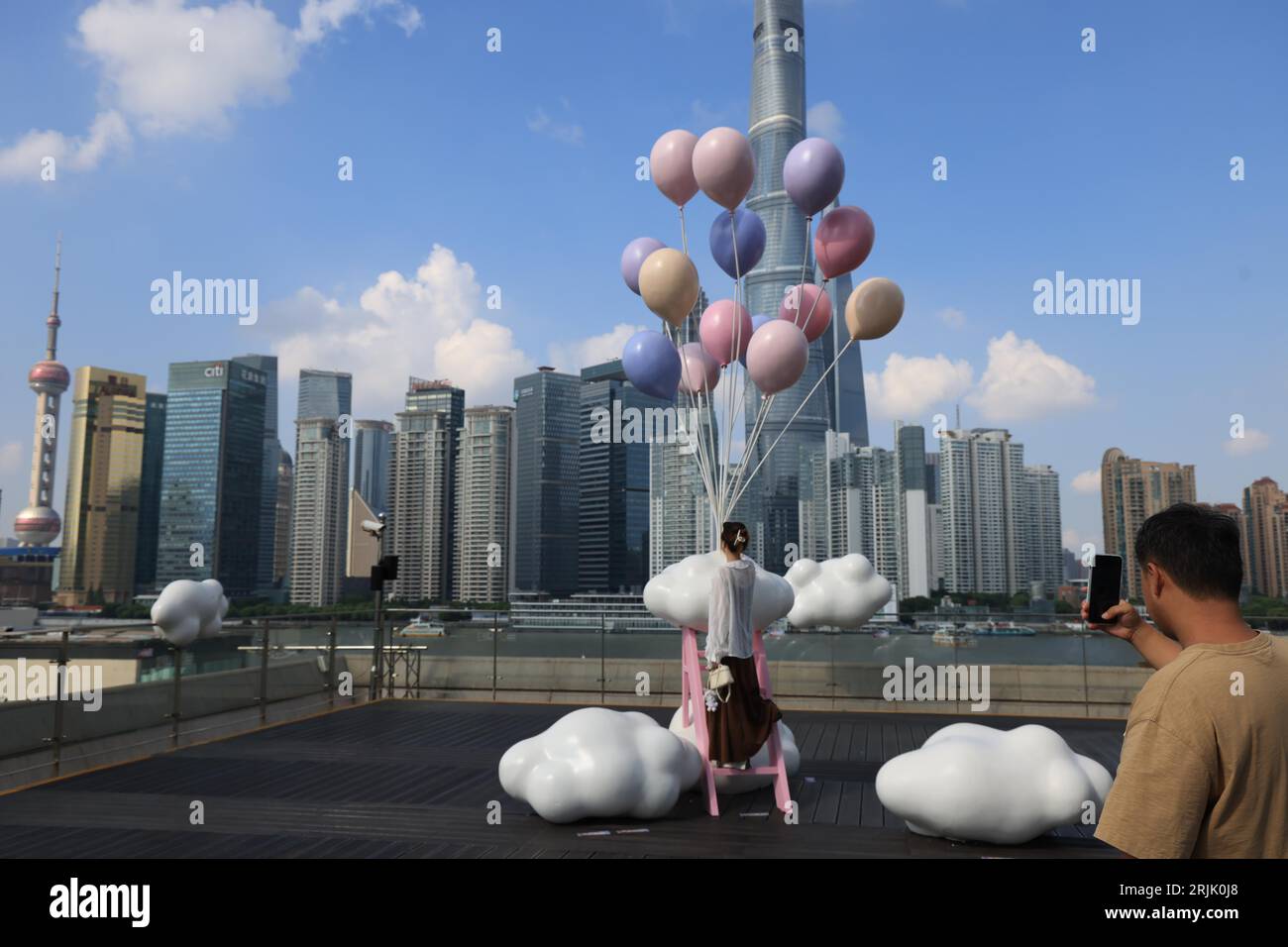 Tourists take photos of a large balloon art installation at the Bund in ...