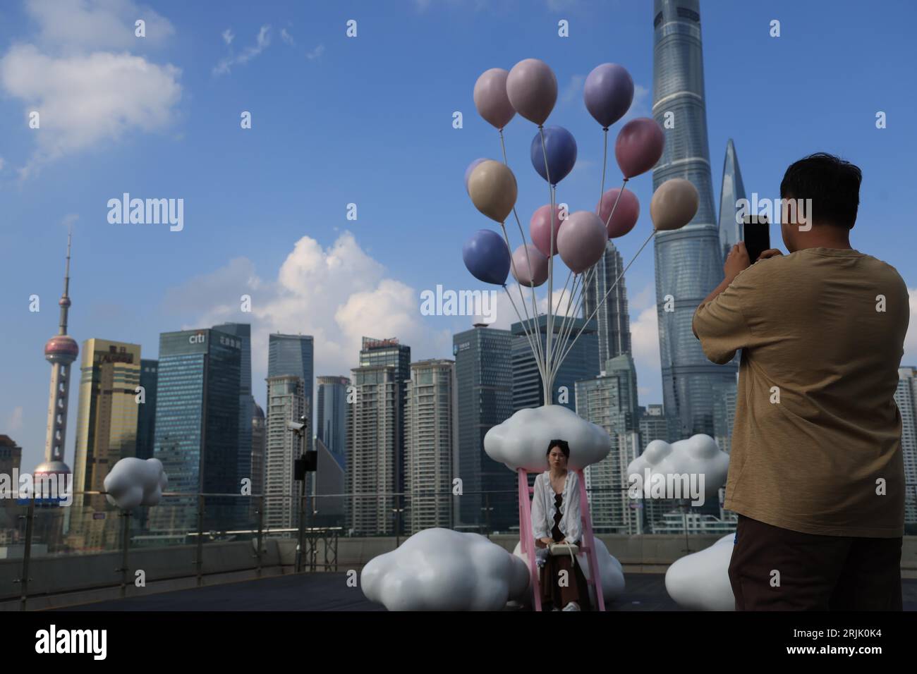 Tourists take photos of a large balloon art installation at the Bund in ...