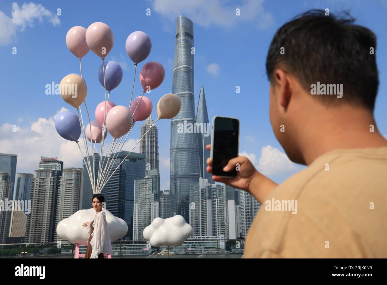 Tourists take photos of a large balloon art installation at the Bund in ...