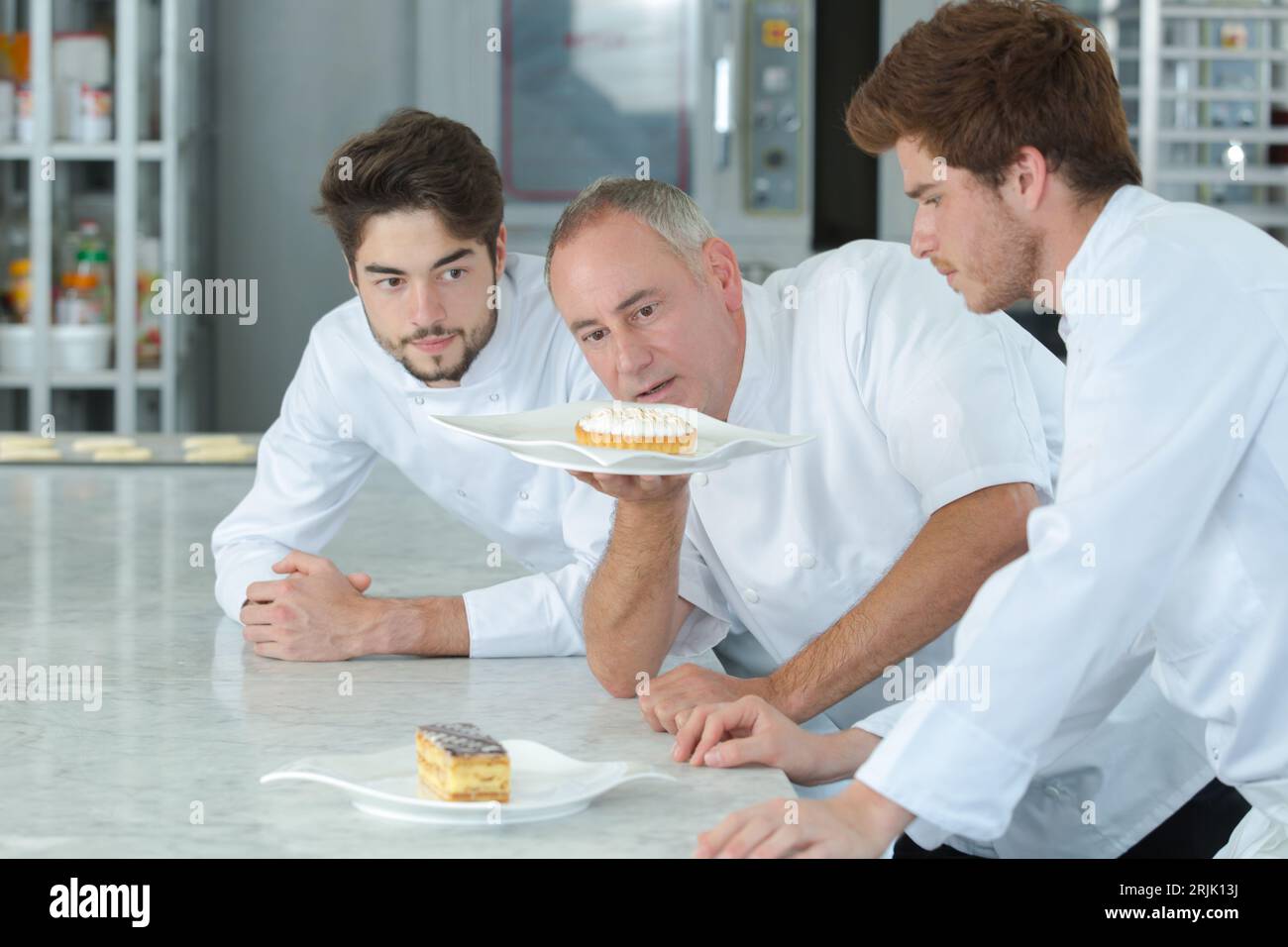 baker instructing apprentice how to present a cake Stock Photo - Alamy