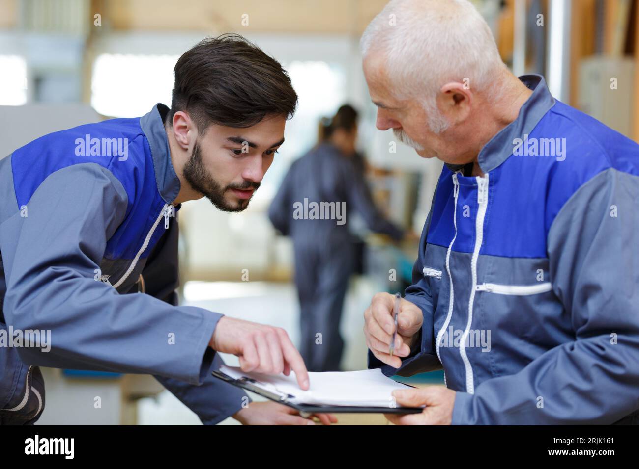 engineer talking to male apprentice at his workstation Stock Photo - Alamy