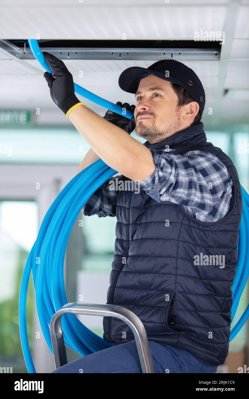 plumber holding a blue pipe above a ceiling Stock Photo - Alamy
