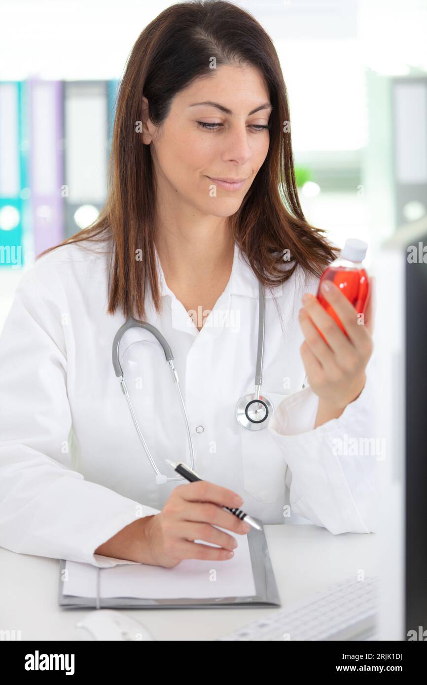 female doctor filling medical form holding medicine bottle Stock Photo ...