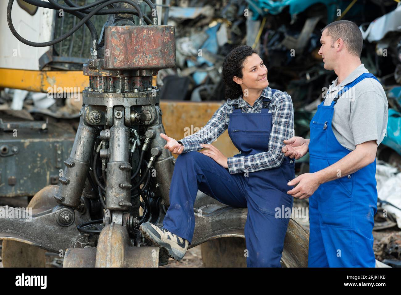 scrap yard workers talking next to grabber hook Stock Photo - Alamy