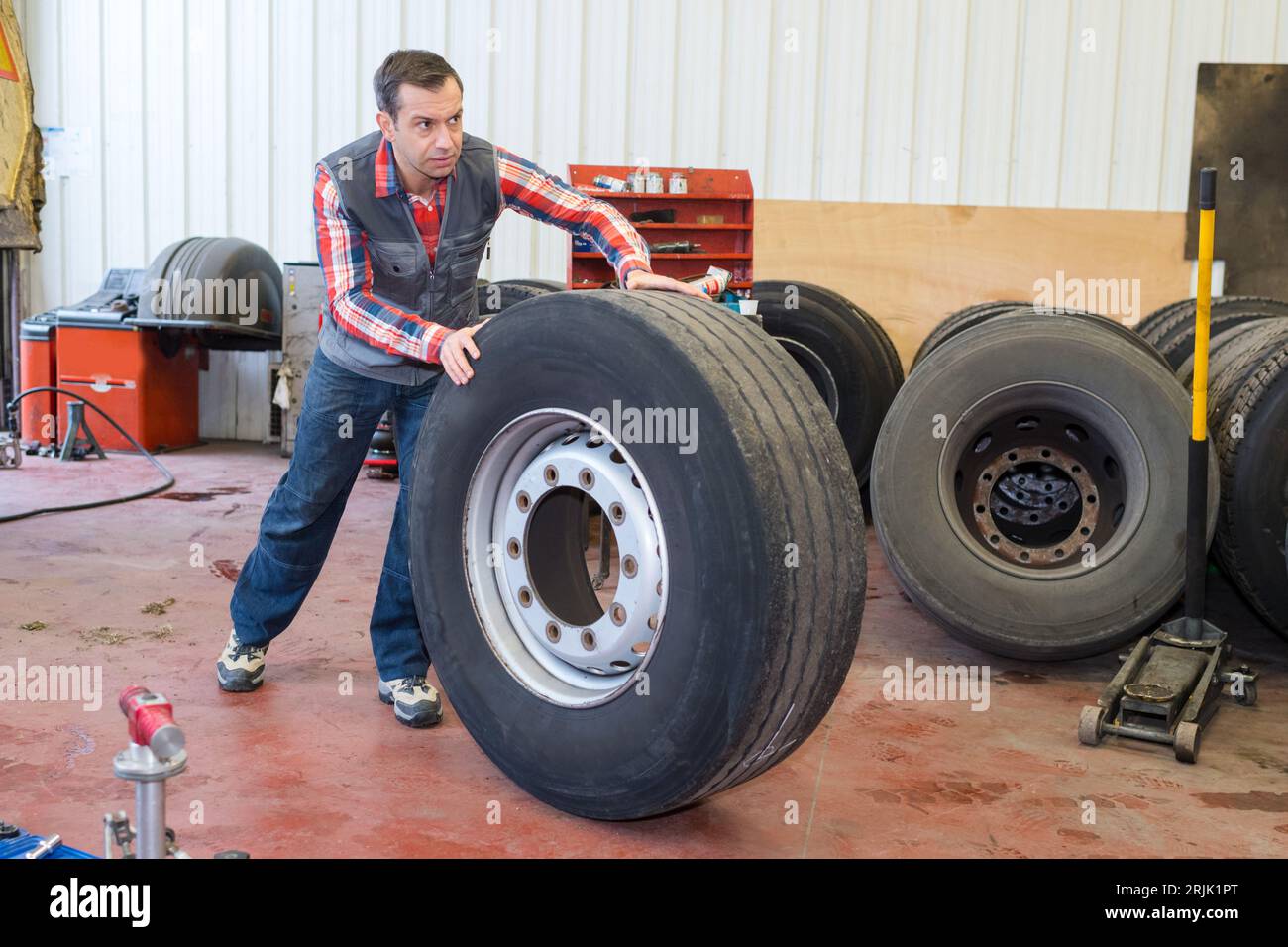 auto mechanic carrying a lorry wheel Stock Photo - Alamy