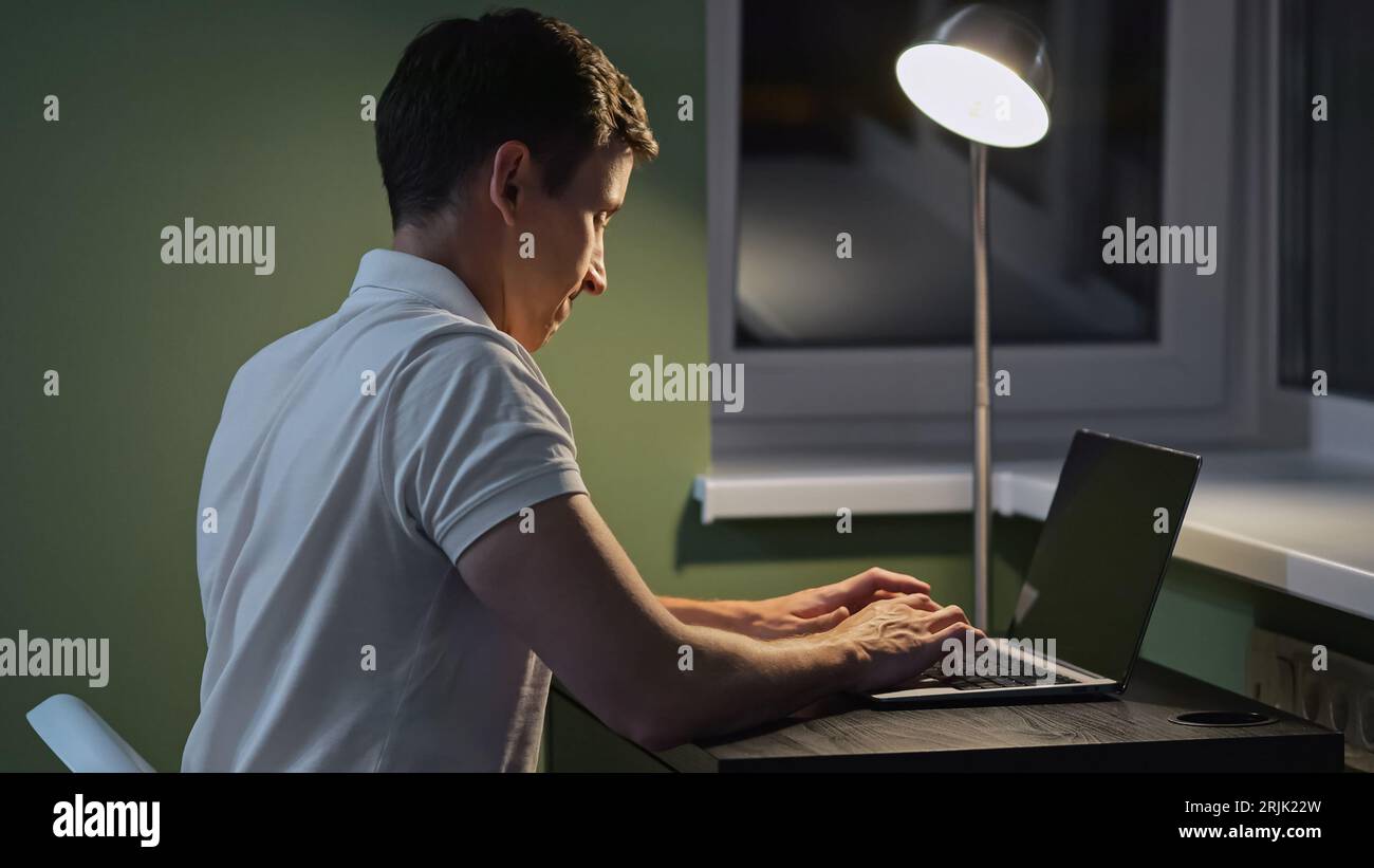 Man types on laptop keyboard in uncomfortable position Stock Photo - Alamy