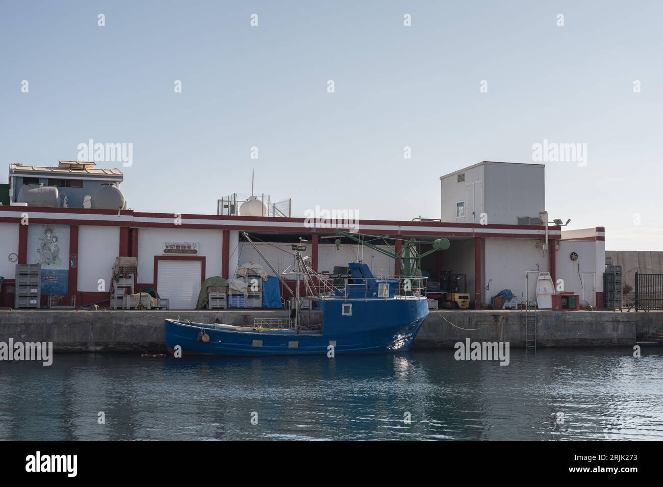 Detail of the pier of the port of Mogan, there is a blue fishing boat ...