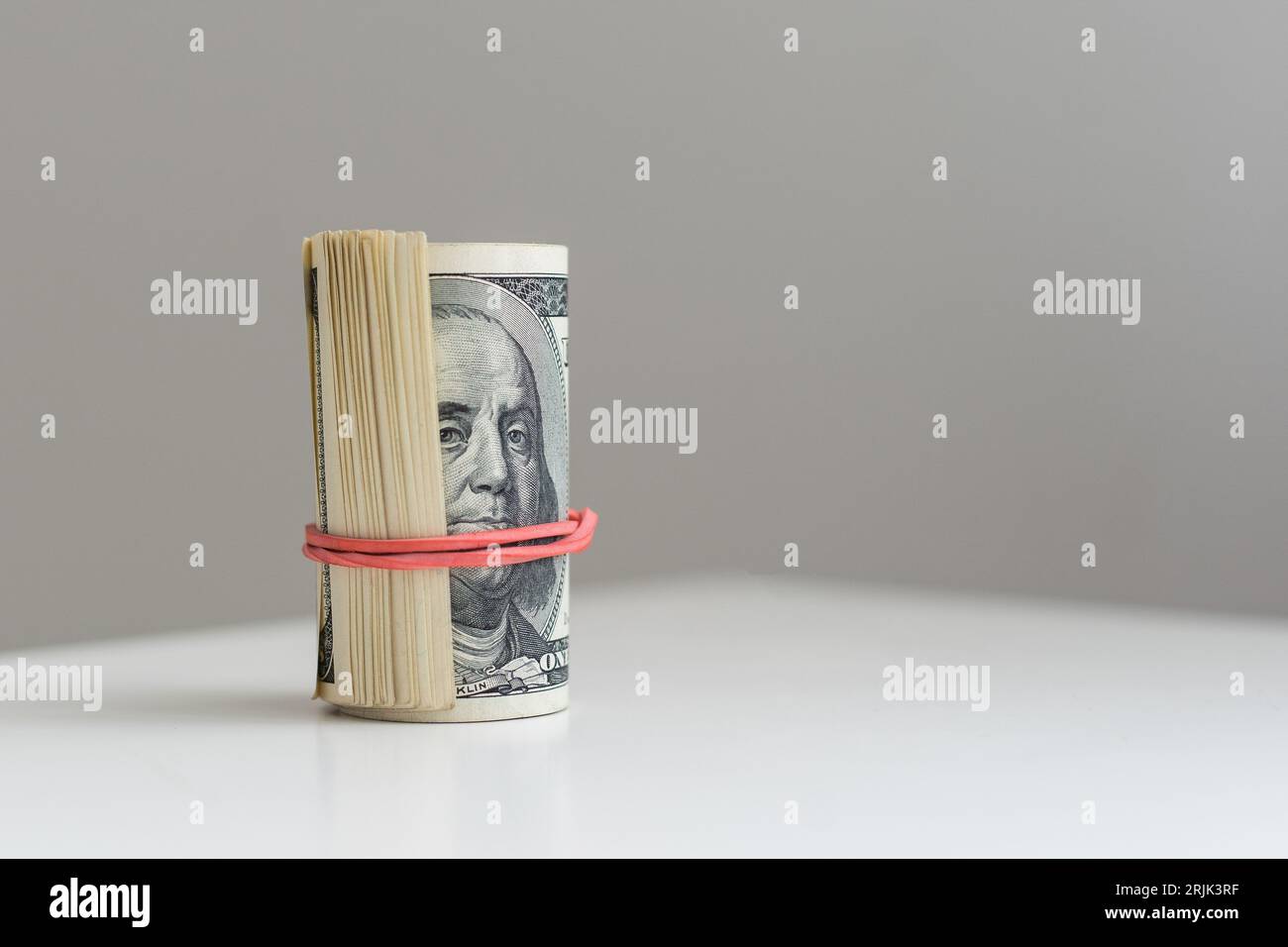 A vertical closeup of a roll of money on light gray background Stock ...