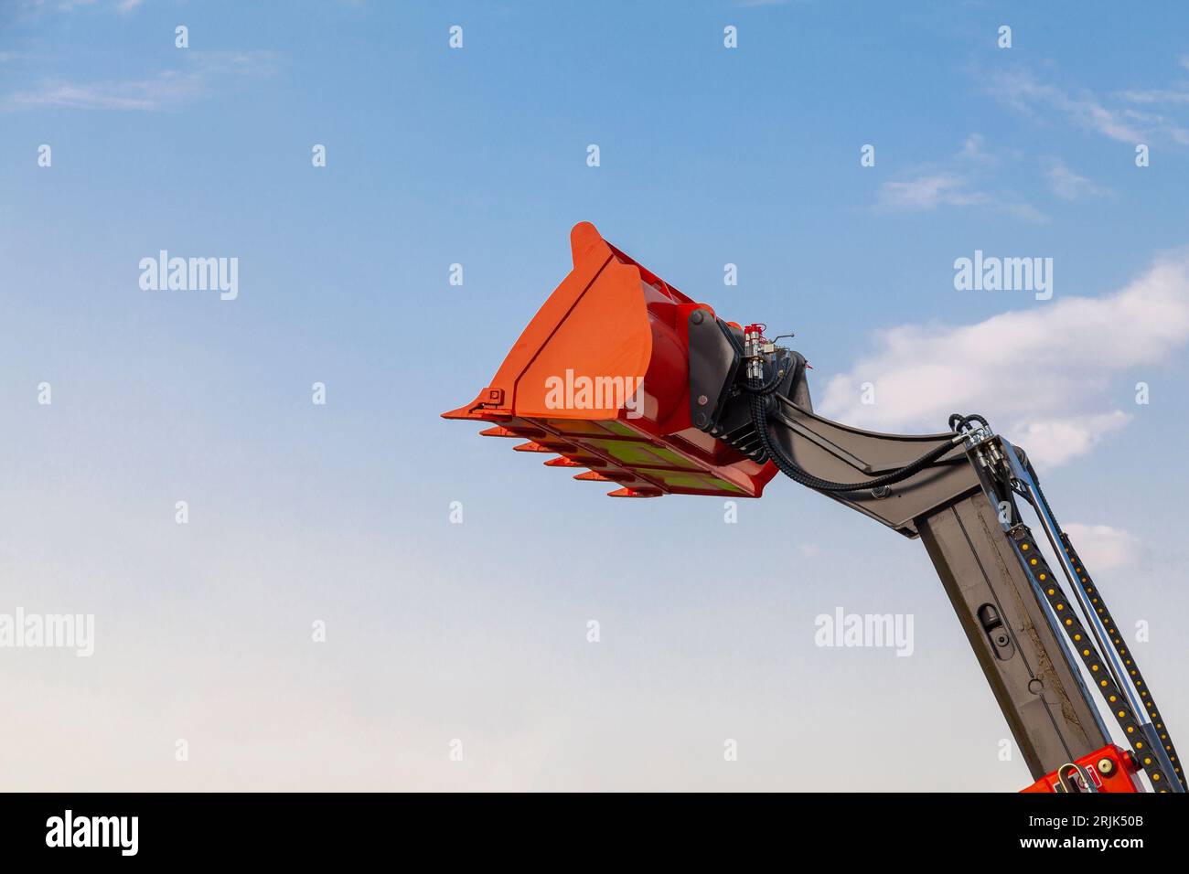 Excavator bucket raised up against a blue sky Stock Photo - Alamy