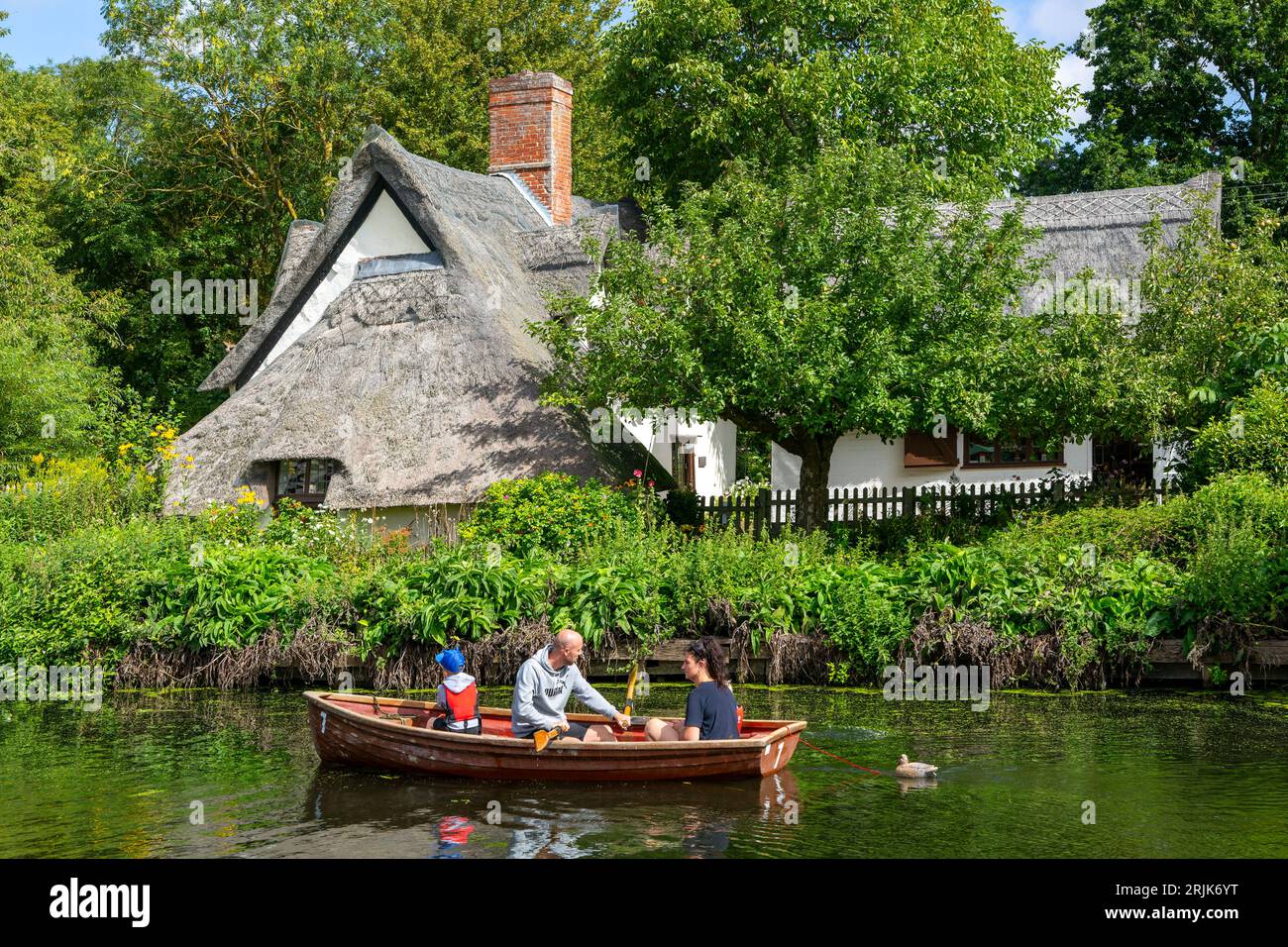 Rowing boat passing thatched Bridge Cottage, Flatford Mill, East ...