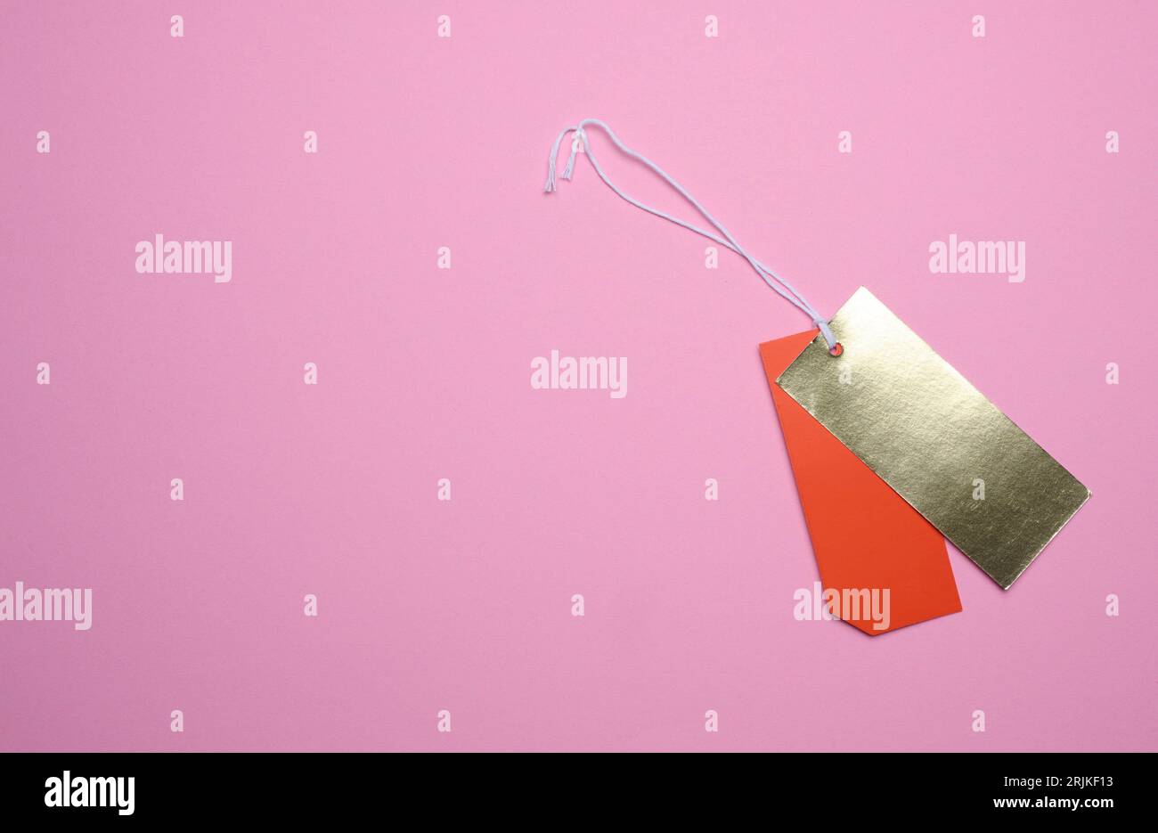 Price tag with a white string for clothing and merchandise on a pink ...