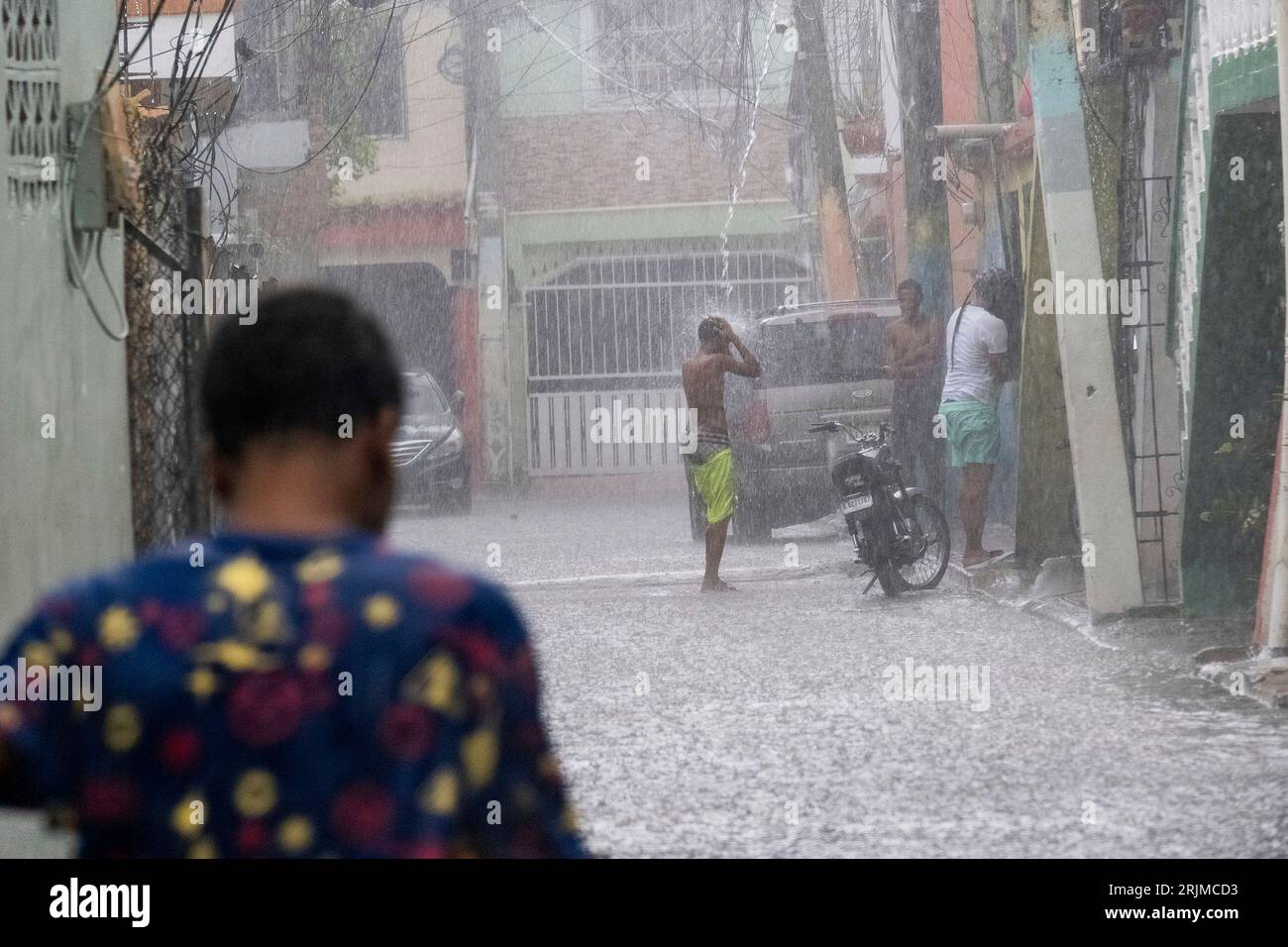 A man stands under a roof drain as the rain of Tropical Storm Franklin ...