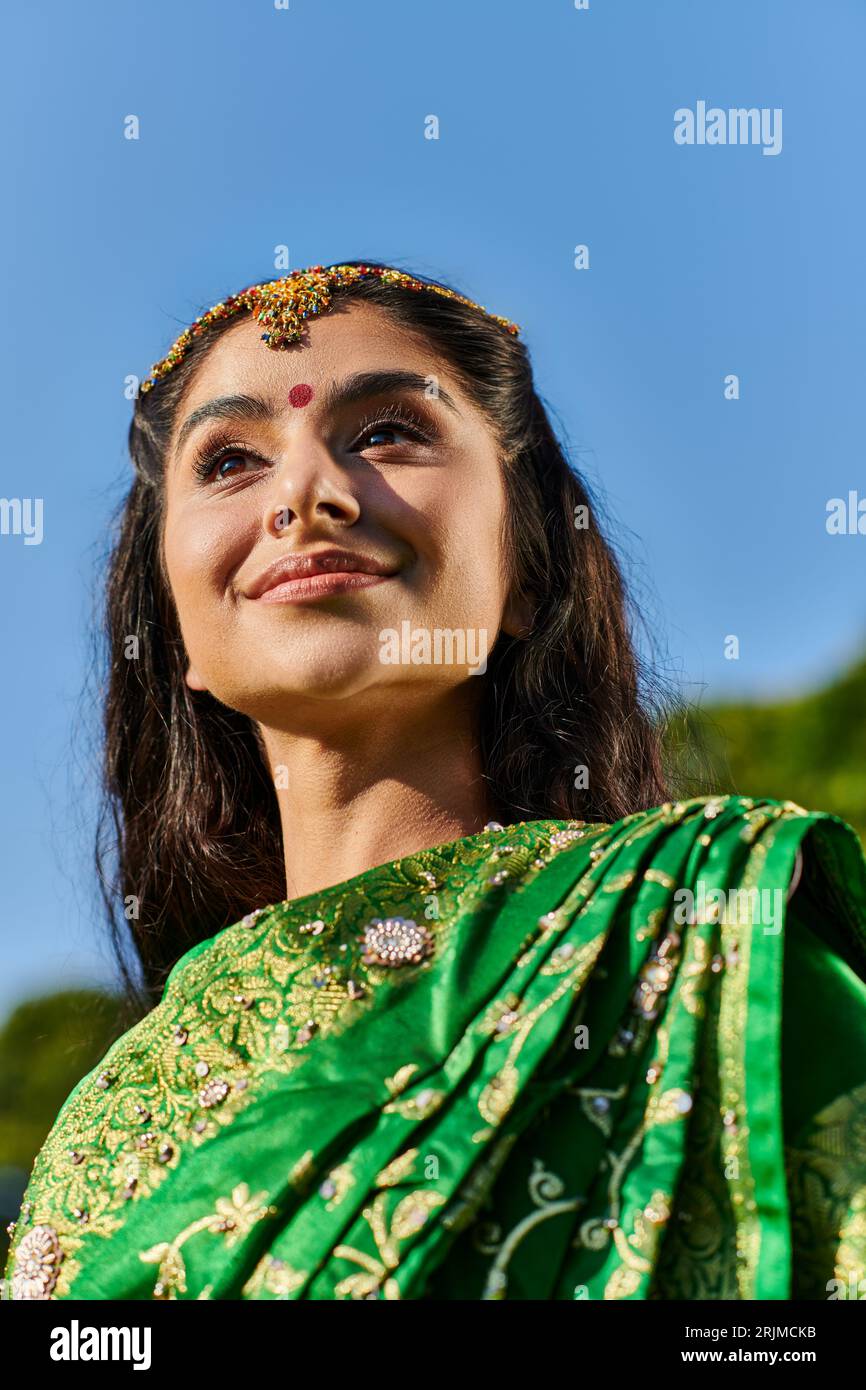 low angle view of cheerful indian woman with bindi and sari standing ...