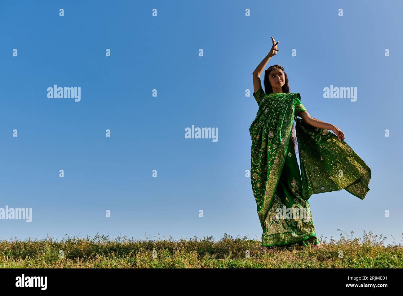 summer dance of smiling indian woman in authentic sari in green field ...