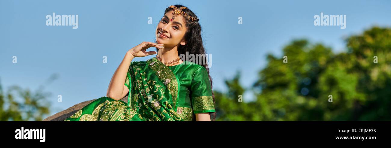 smiling indian woman in green sari and matha patti posing at camera ...