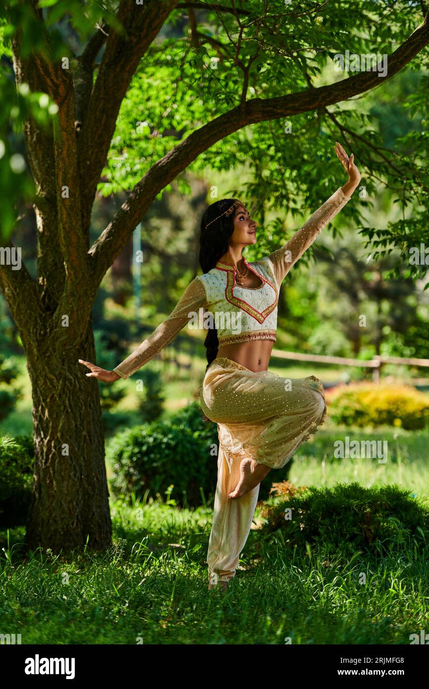young indian woman in traditional attire dancing on green lawn under ...