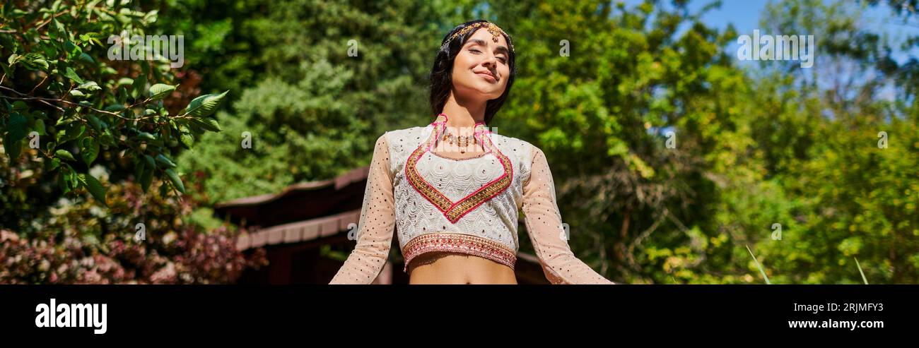 summer park outing, indian woman in traditional wear smiling with ...