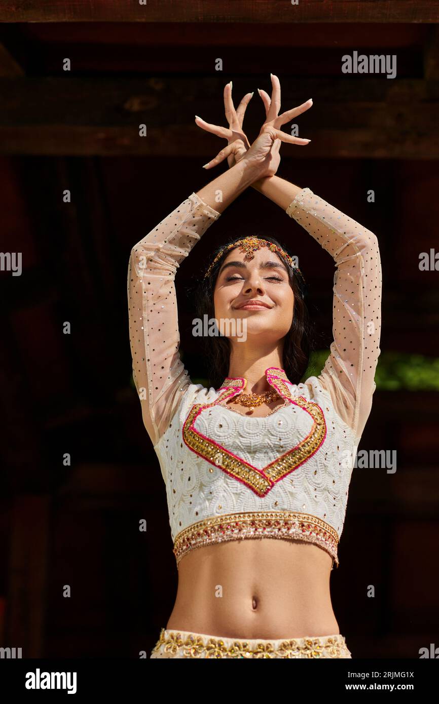 joyful young indian woman in elegant ethnic wear dancing with closed ...