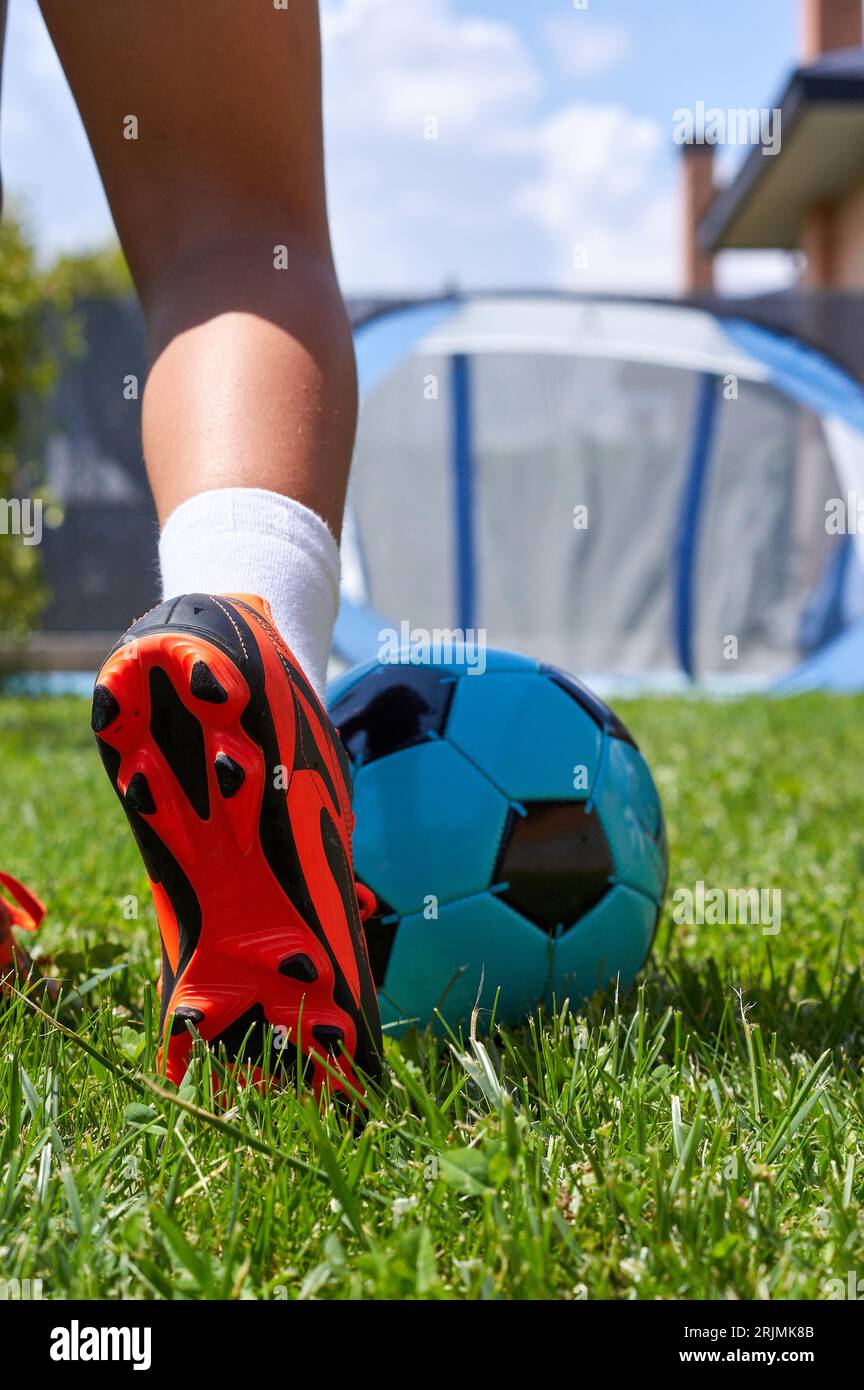 A female athlete playing soccer with bright orange soccer boots and a ...