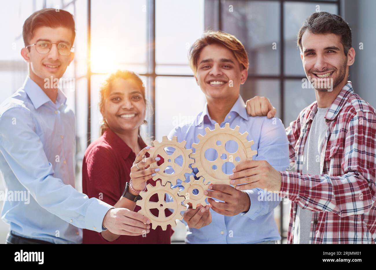 Business people or office workers hold wooden gears that symbolize well ...