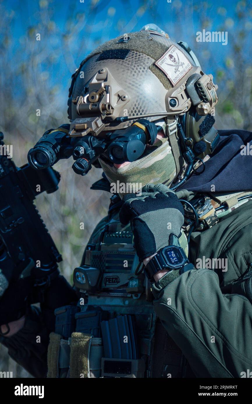 A military personnel stands in a rural outdoor environment wearing a ...