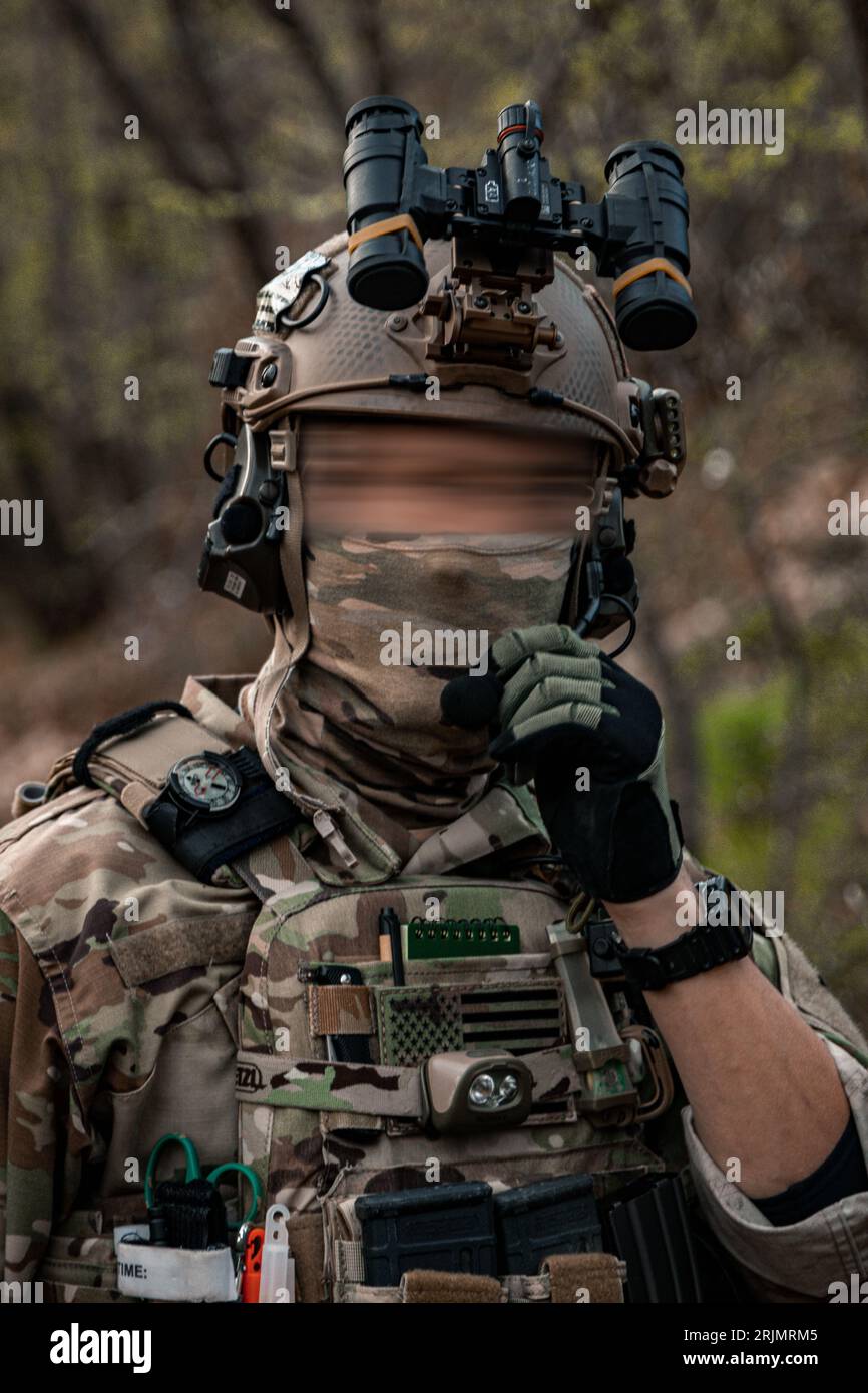 A military personnel stands in a rural outdoor environment wearing a ...