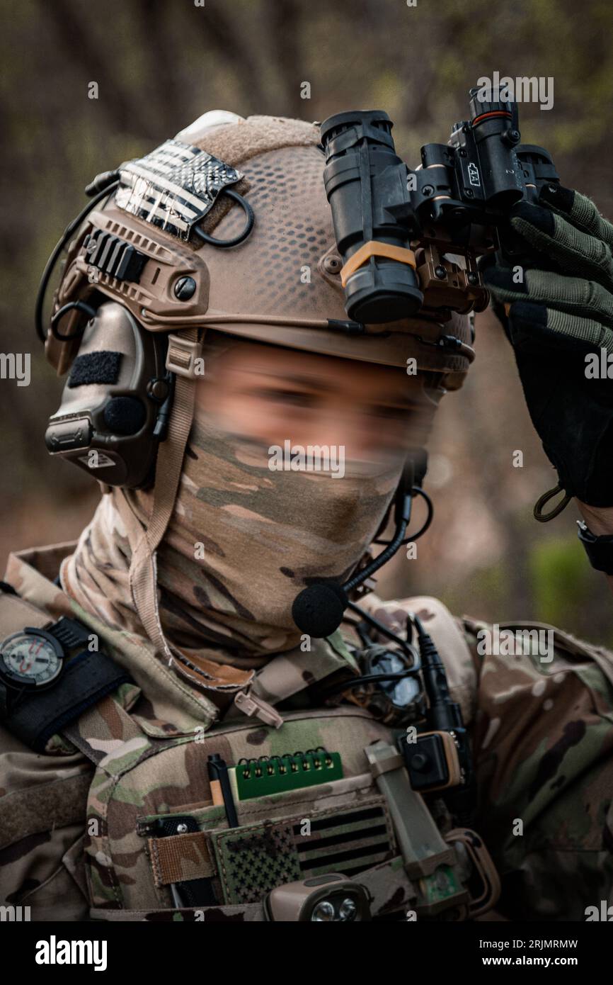A military personnel stands in a rural outdoor environment wearing a ...