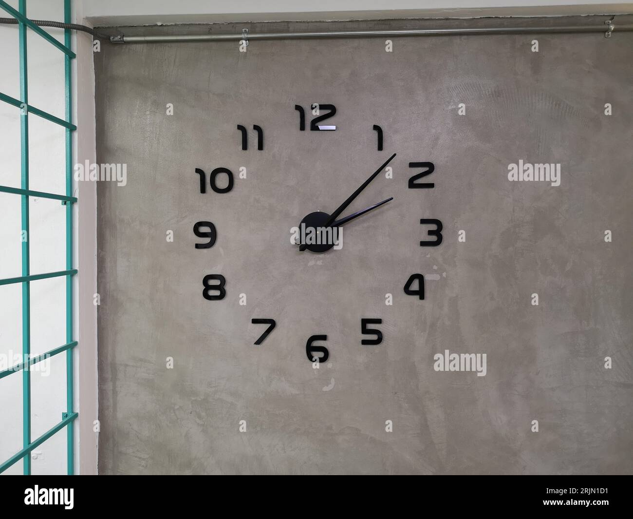 An elegant black wall clock is displayed in the lobby of a modern ...