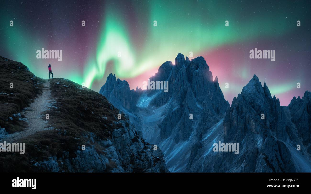 Northern lights and young woman on mountain peak at night Stock Photo ...