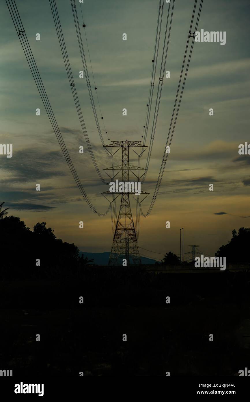 An aerial view of a power line illuminated at dusk, surrounded by a ...
