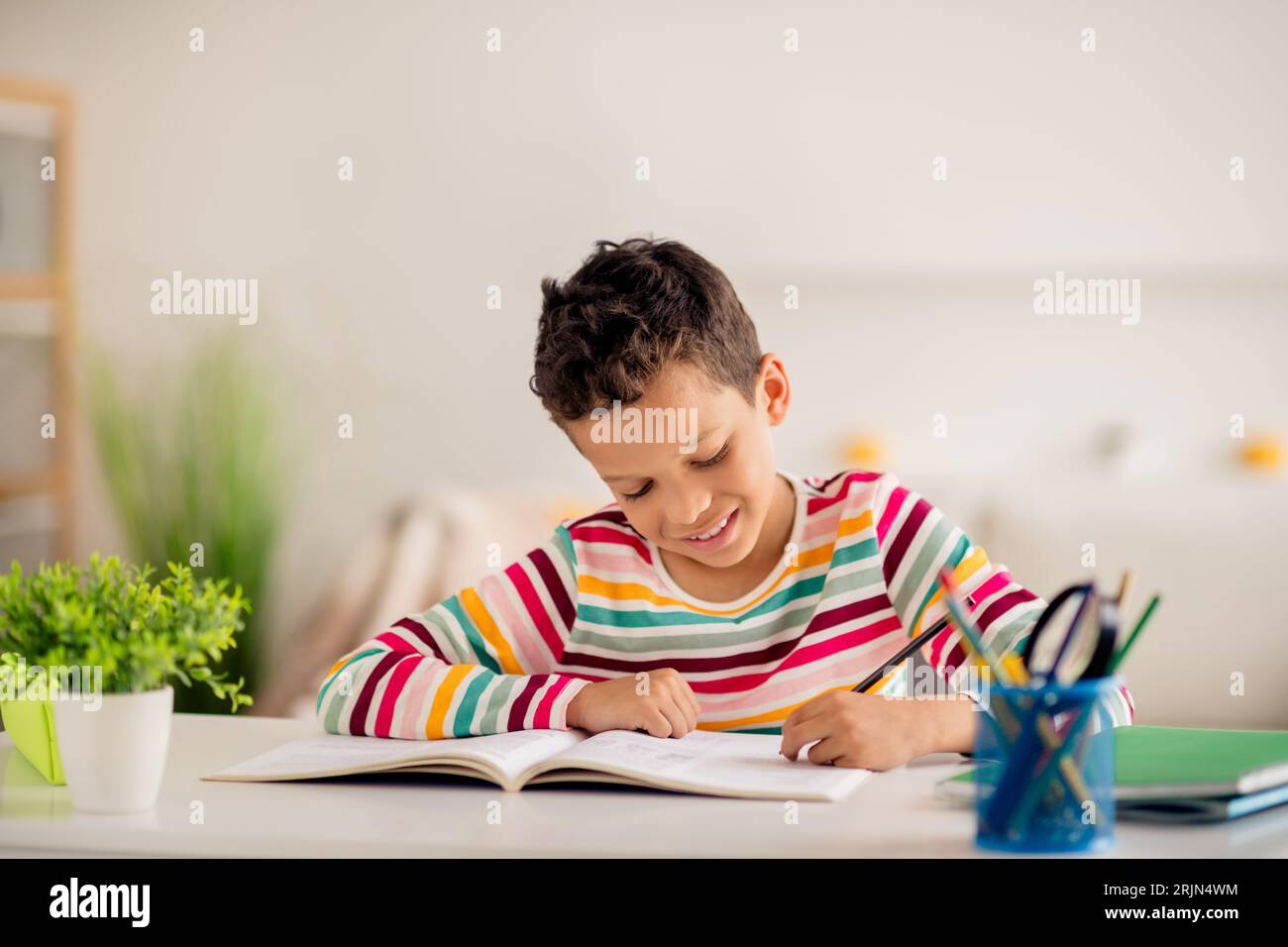 Photo of smart pupil kid sitting table writing notebook doing class ...