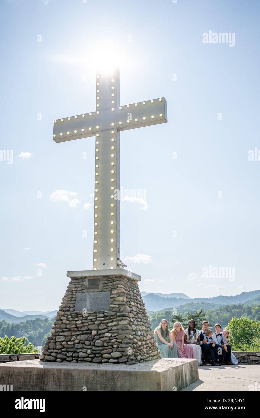 A group of people in an outdoor setting, looking at a large, white ...