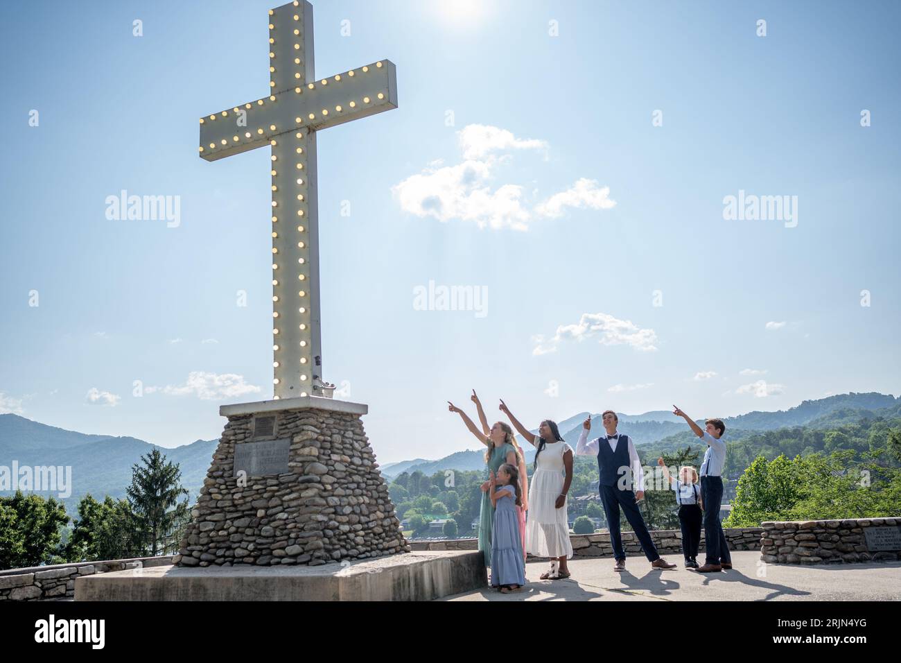 A group of people in an outdoor setting, pointing towards a large ...