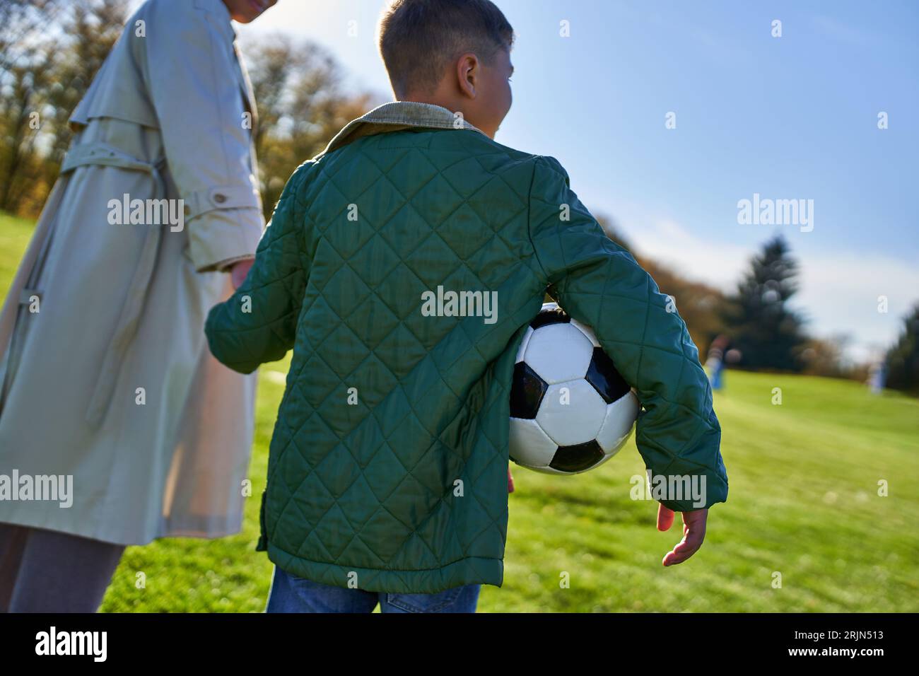 african american boy holding football, walking with mom on field ...