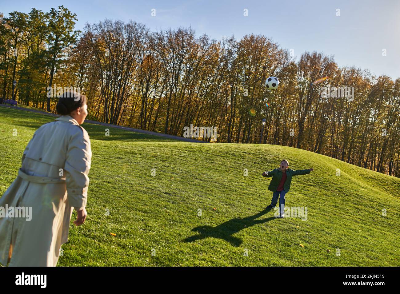 amazed african american boy playing football with mother on green field ...