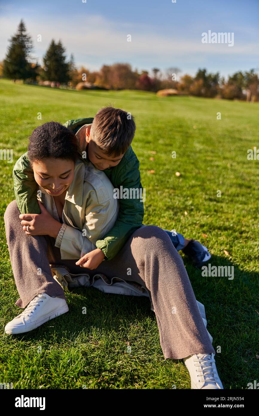 Happy Mother And Son Sitting On Grass Sunny Day Autumn Playful
