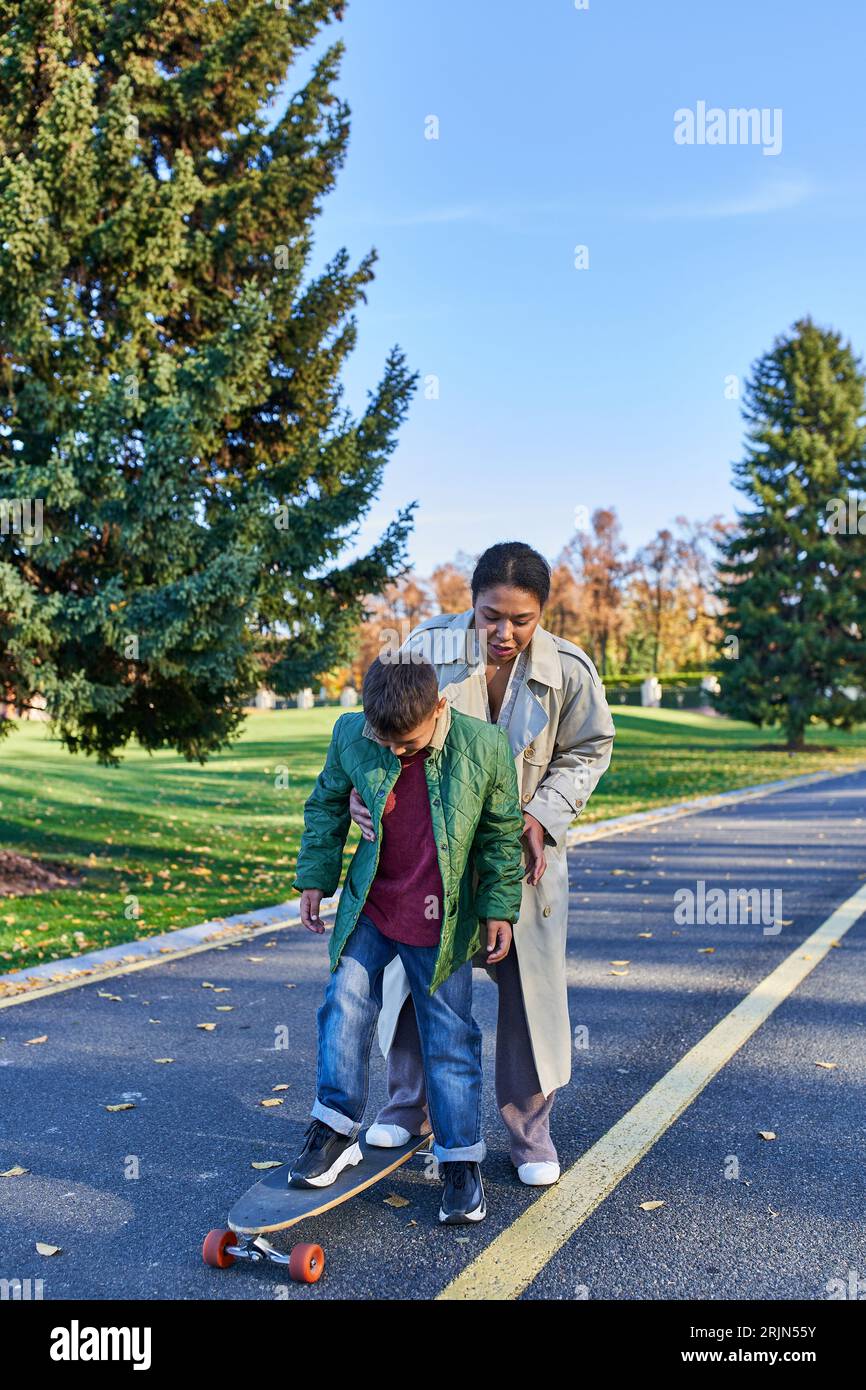 mother and son in autumn park, african american woman teaching boy how ...