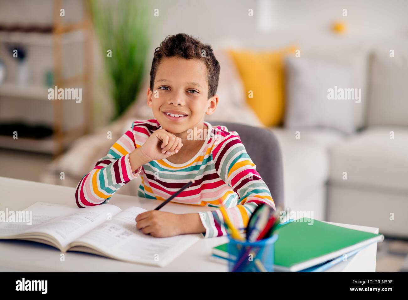 Photo of clever kid learning in modern school interior class writing ...