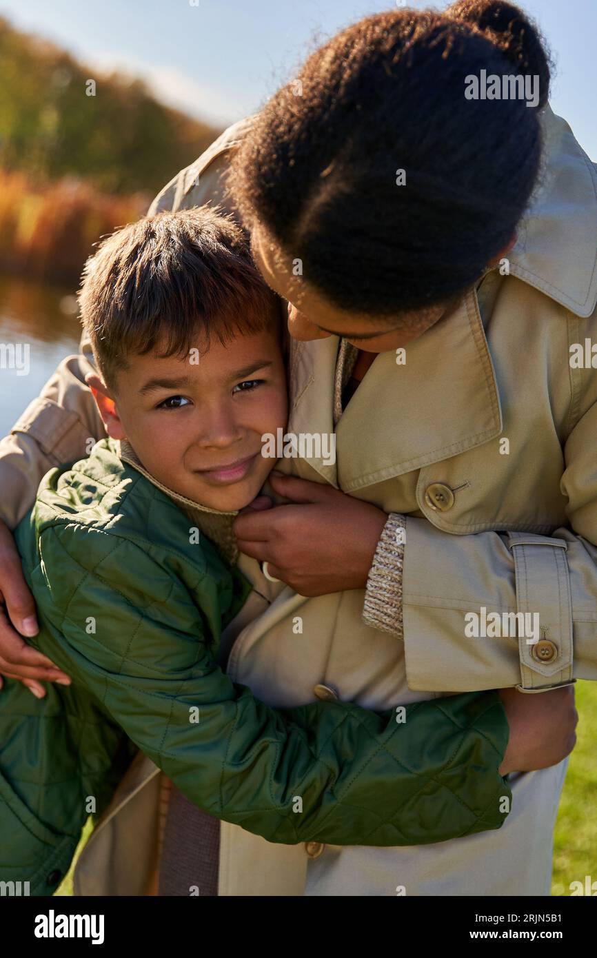 woman calming upset boy, african american mother and child, family bonding, autumnal nature ...