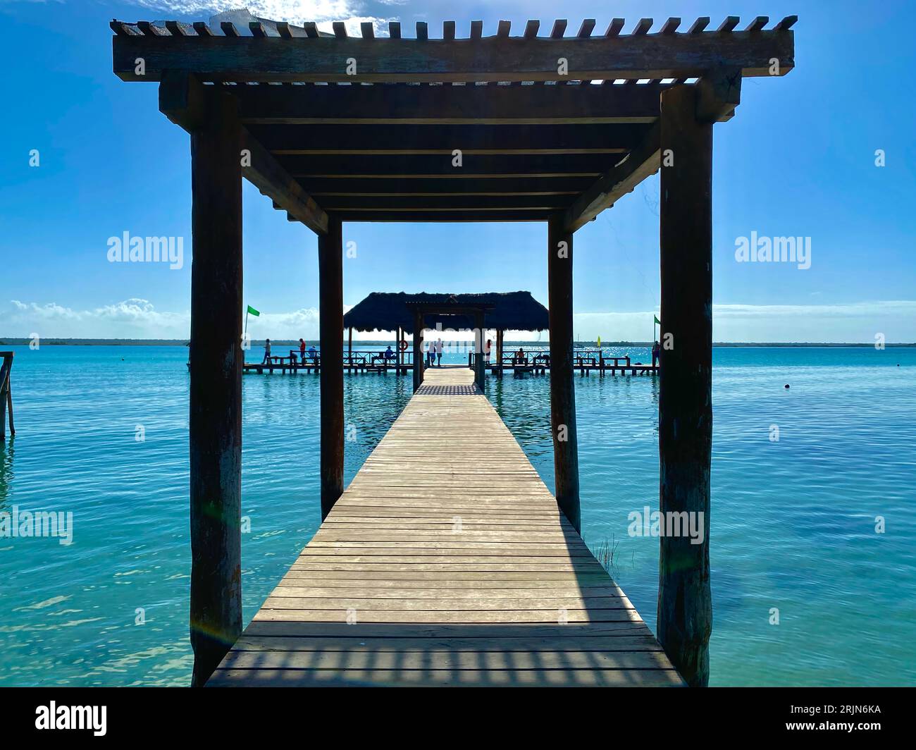 A tranquil pier atop a crystal-clear blue body of water, with wooden ...