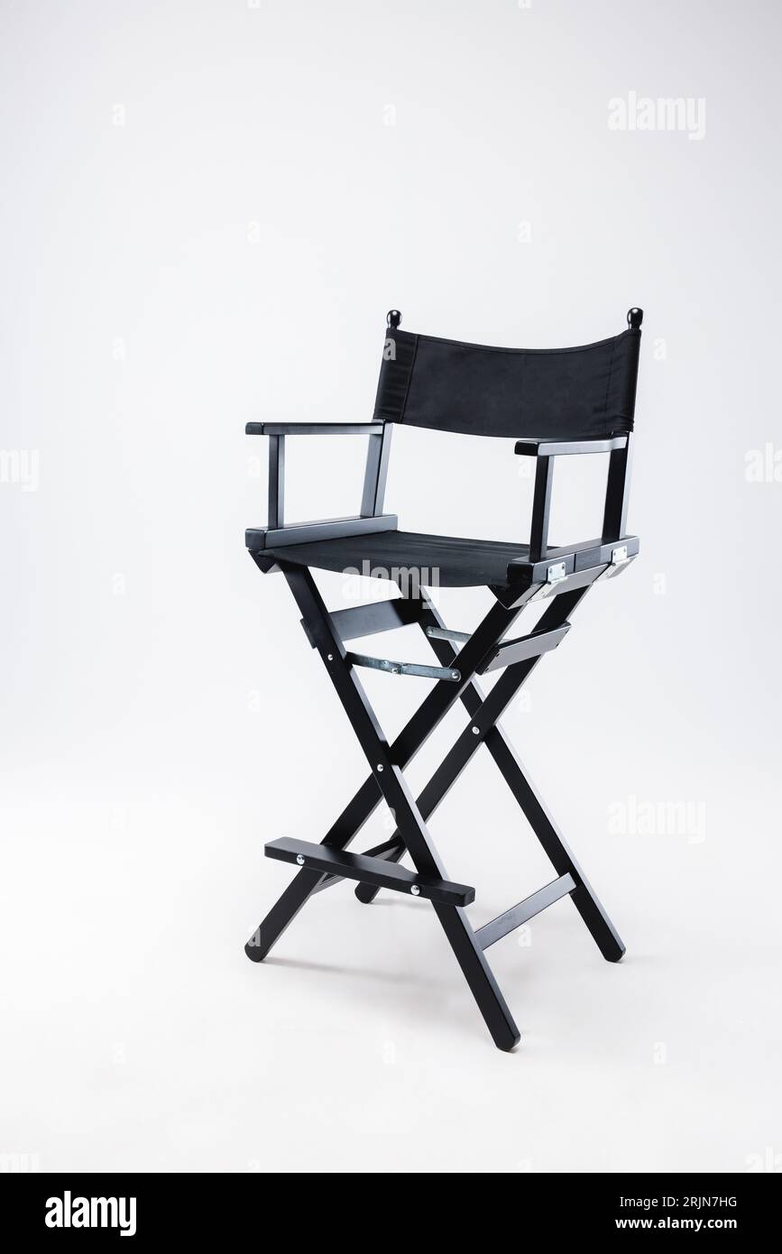 A black and white director's chair stands against a plain white ...